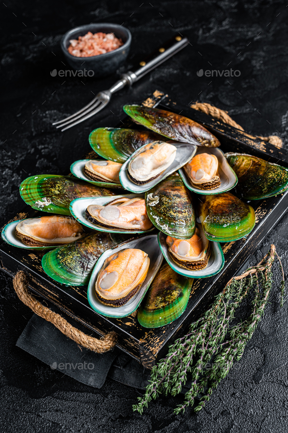 Boiled Green mussels with herbs in a wooden tray. Black background. Top ...
