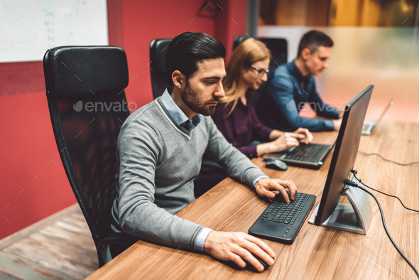 Group of people at a start up company working on their computers ...