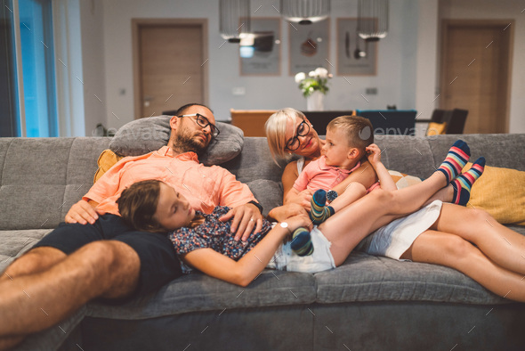 Loving family of four resting on the sofa, cuddling together Stock ...