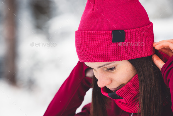 Close up woman putting on a red hat matching her red scarf, while on a ...