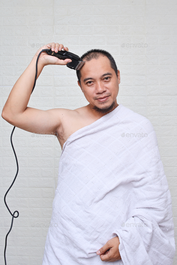 Muslim man wearing white ihram clothes doing Tahallul, shaving their ...