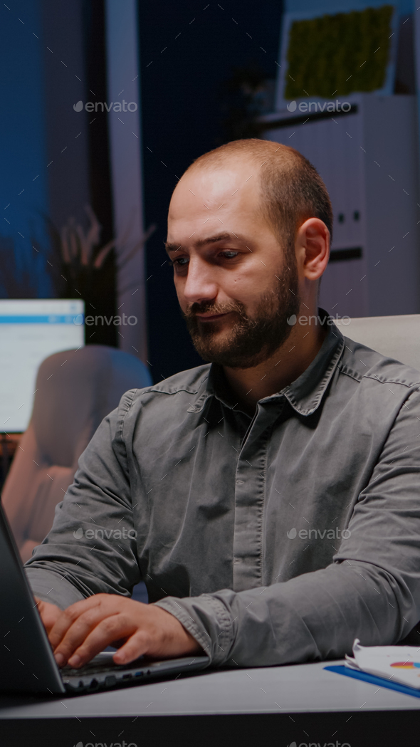 Overworked businessman typing financial statistics on laptop sitting at ...
