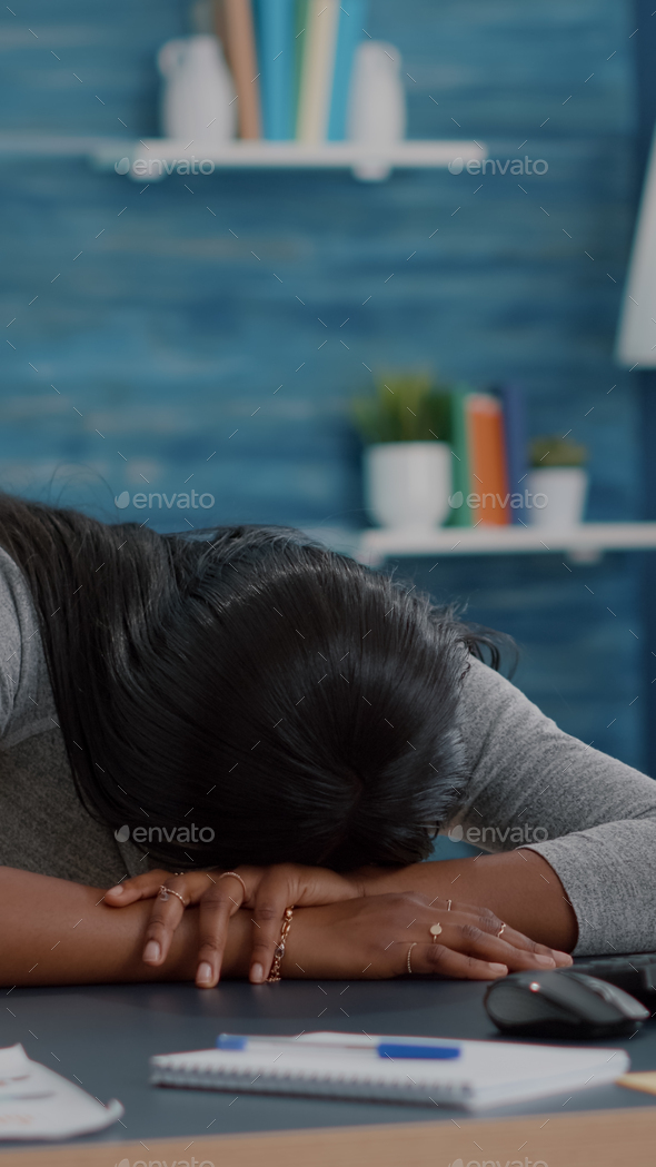 Disappointed workaholic student sleeeping on desk table in living room ...