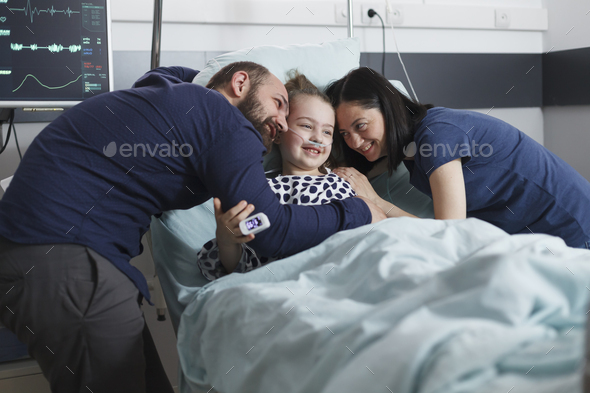 Happy young parents hugging ill hospitalized recovering little girl ...