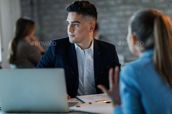 Young businessman ignoring his female colleague while she talking to ...