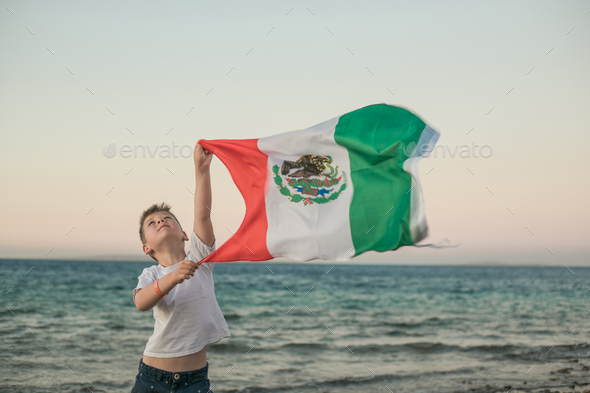 Little boy lets the Mexico flag fly the Sea. Stock Photo by sokorspace