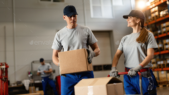 Happy warehouse workers talking while preparing cardboard boxes for ...