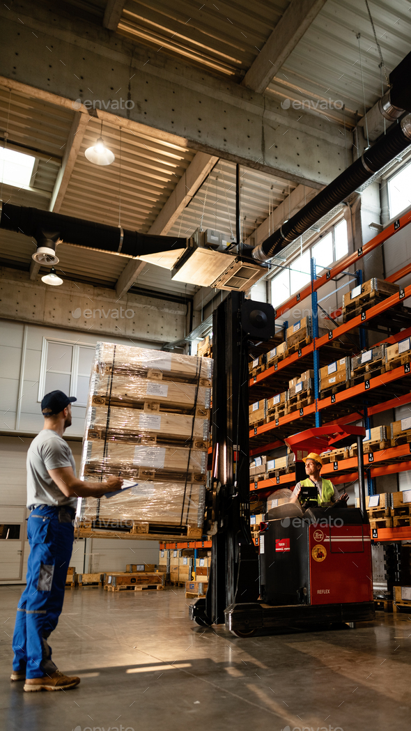Forklift operator loading pallets while dispatcher is supervising ...