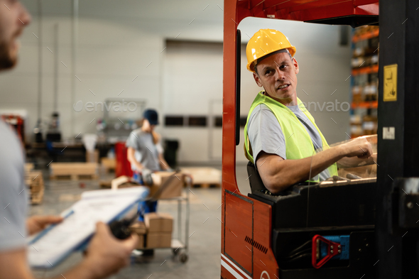 Forklift operator talking with a foreman in industrial warehouse. Stock ...