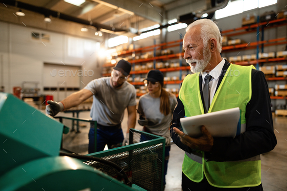 Senior businessman in quality control inspection at factory warehouse ...