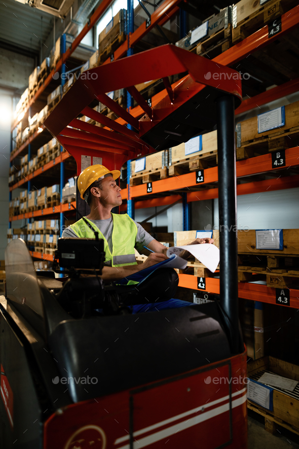 Forklift operator taking notes while working in a warehouse. Stock ...