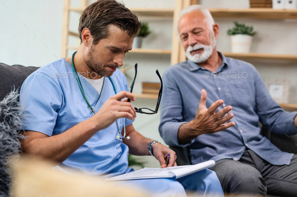 General practitioner analyzing medical documents of senior patient ...