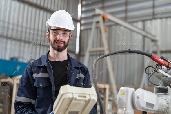 Male automation engineer using remote controller control robot arm welding machine in factory ...