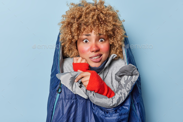 Young curly female camper trembles from cold clatters teeth has red ...
