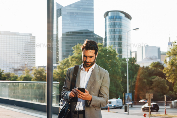 urban business man looking at his smart phone outdoors in downtown ...