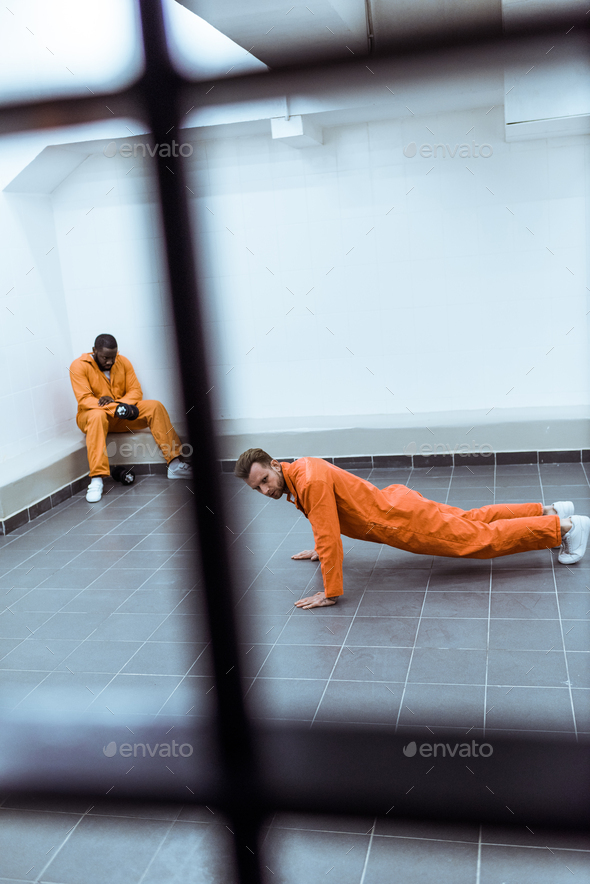 prisoner doing push-ups in prison cell Stock Photo by LightFieldStudios