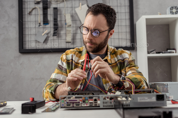 man using multimeter while fixing pc Stock Photo by LightFieldStudios