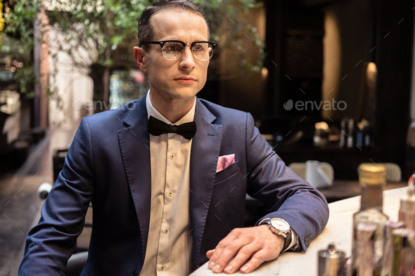 handsome man in stylish suit sitting at bar counter of luxury ...