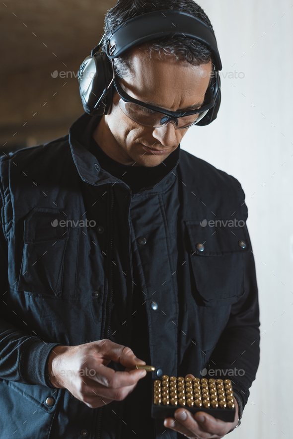 handsome man taking bullet from box Stock Photo by LightFieldStudios