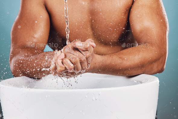 Man, water splash and hands by basin for skincare, hygiene or wash against studio background ...