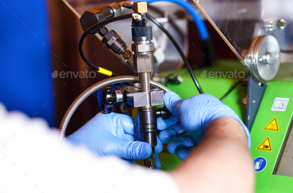 Professional mechanic testing diesel injector in his workshop. Stock ...