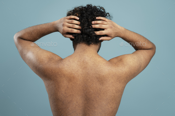 Rear view shirtless dark-haired curly man scratching head or massaging ...
