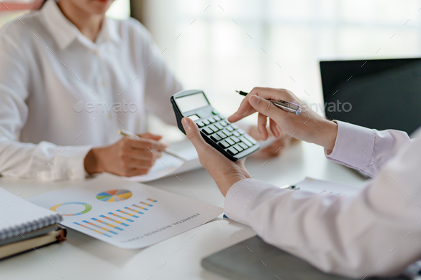Business people in a meeting and using a calculator to calculate, plan ...