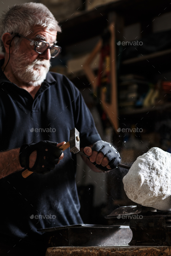 Senior sculptor working on his marble sculpture in his workshop with ...