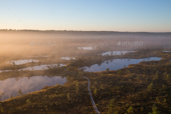 View on the fog clad peat bog with bog lakes and wooden boardwalk Stock ...
