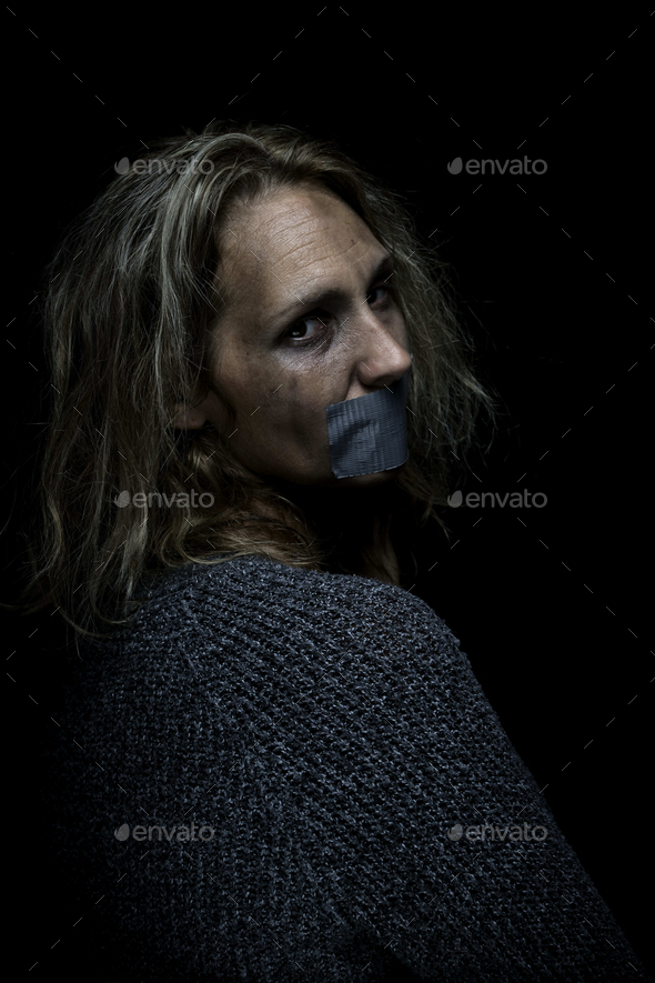 Vertical shot of an abused and scared woman on black background ...