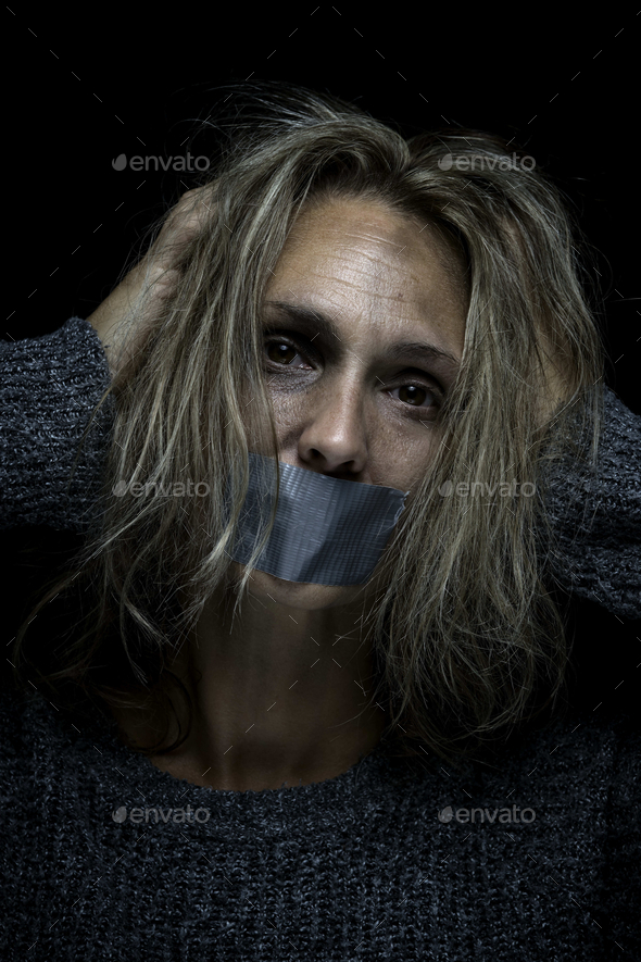 Vertical shot of an abused and scared woman on black background ...