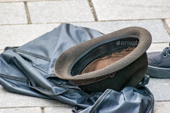 Hat on a leather jacket in front of a beggar Stock Photo by wirestock