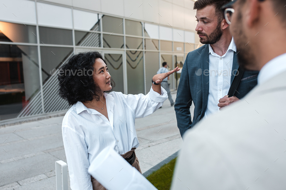 Coworkers standing outside in front of office buildings discuss about ...