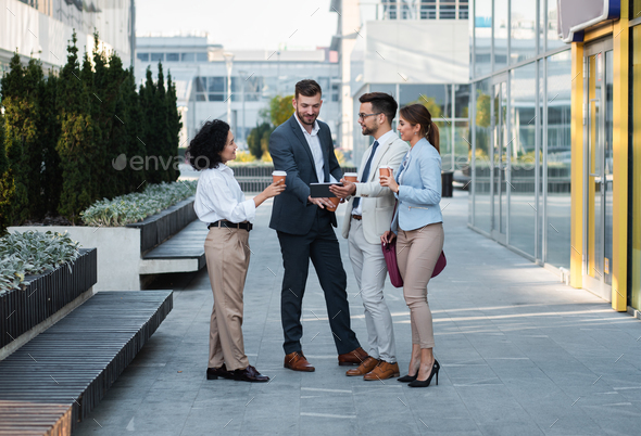 Coworkers standing outside in front of office buildings discuss about ...