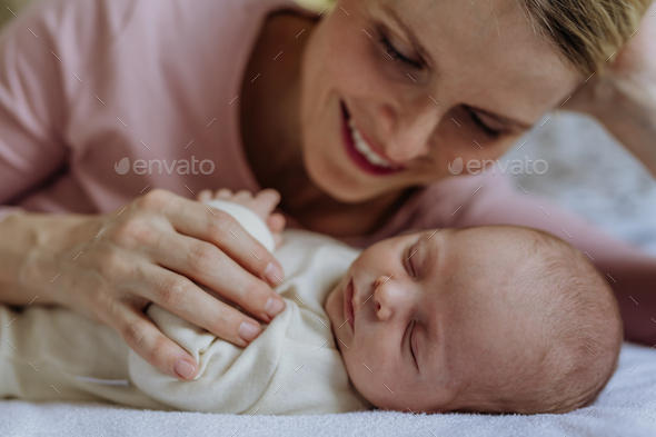 Mother cuddling with her newborn baby in their bad. Stock Photo by ...