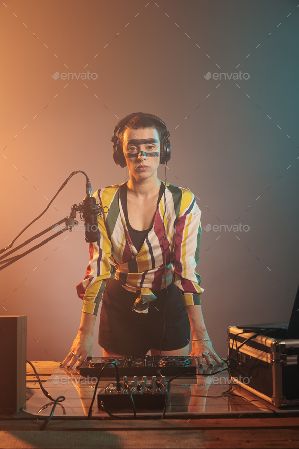 Female DJ standing at turntables and mixing Stock Photo by DC_Studio