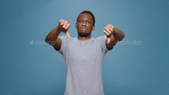 Disappointed person showing thumbs down symbol in studio Stock Photo by ...
