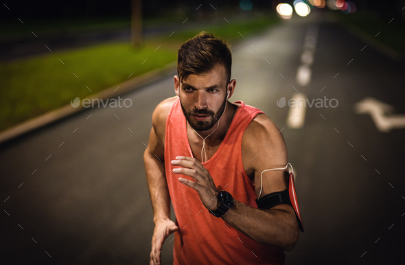 Man running through the city street at night. Stock Photo by zoranzeremski