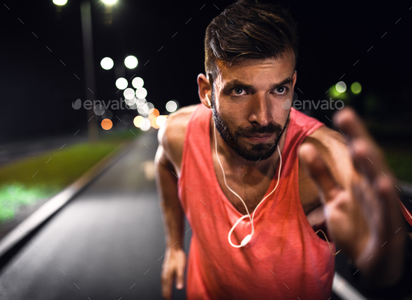 Man running through the city street at night. Stock Photo by zoranzeremski