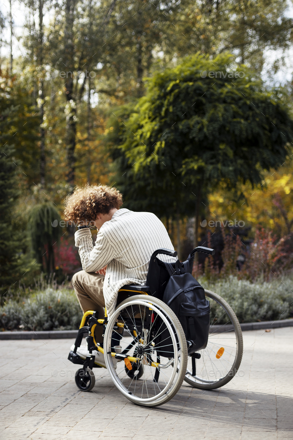 Upset, disabled guy sitting in a wheelchair on the street. A young man ...