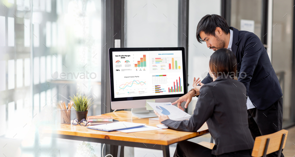 Team of confident Asian business people point to graphs and charts to ...