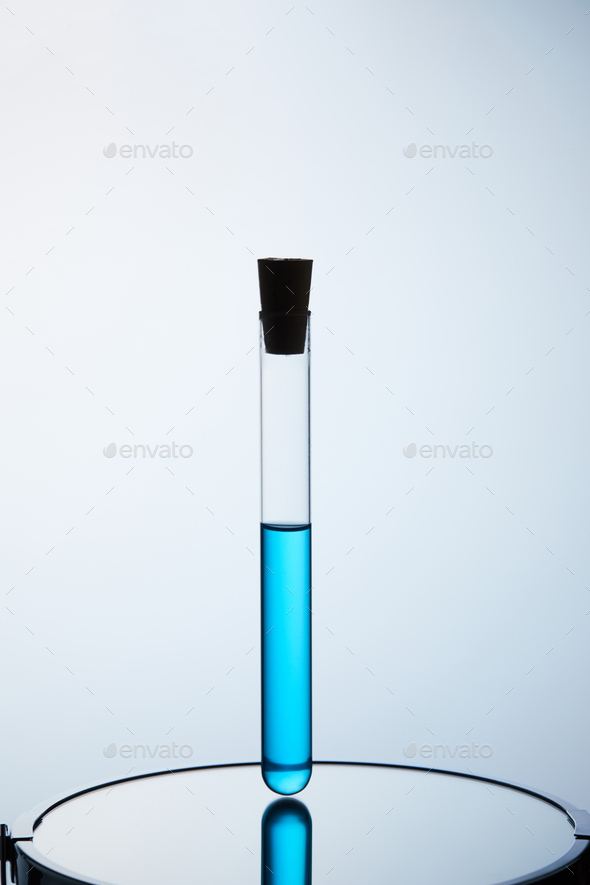 test tube filled with blue liquid standing on reflective surface Stock ...