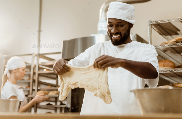happy handsome african american baker preparing dough on baking ...