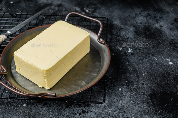 Butter block in steel kitchen tray. Black background. Top view. Copy ...