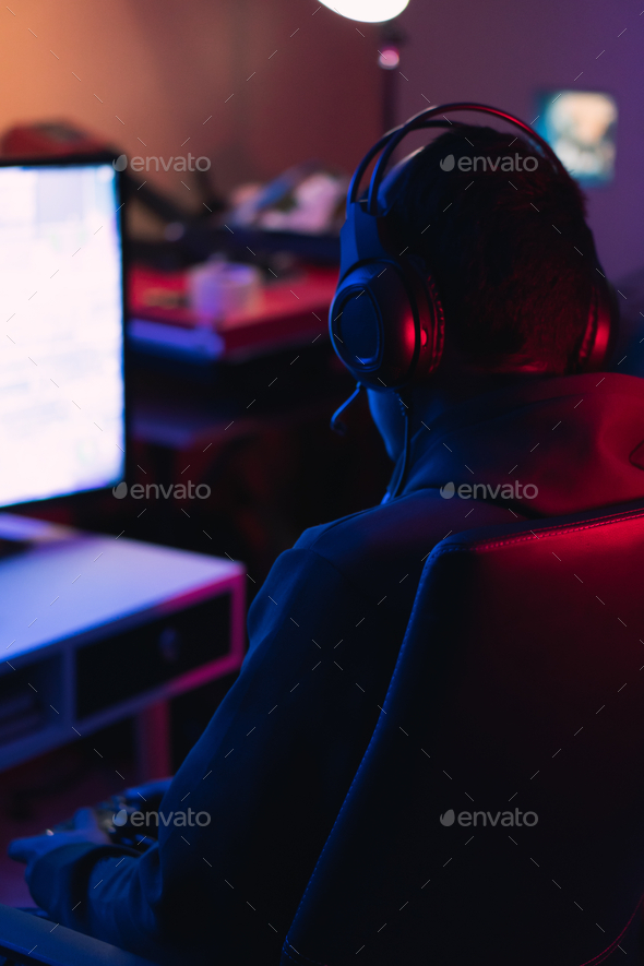 Shallow focus of a male gamer with headphones streaming a live video ...