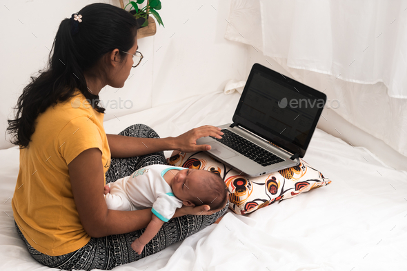 Young Hispanic mother with a baby working from home on a laptop Stock ...
