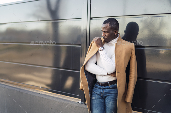 Shallow focus shot of a stylish handsome African male in a coat posing ...