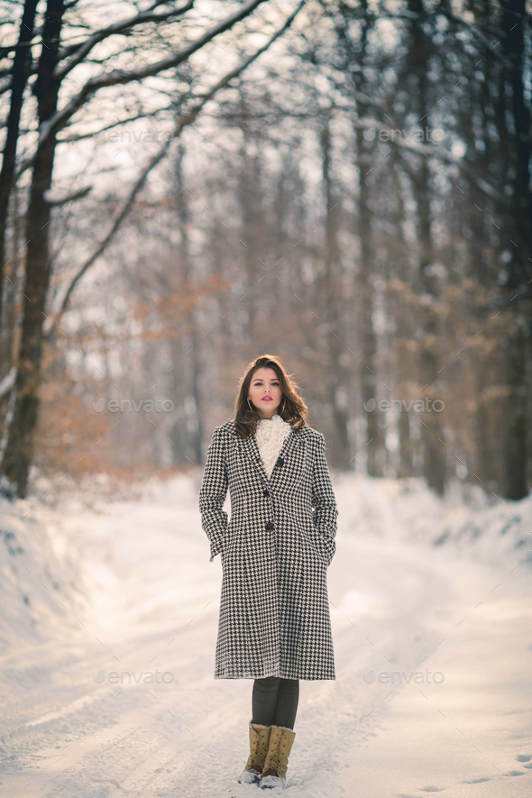 Full body shot of a brunette girl in a stylish winter outfit walking ...