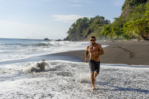 Young shirtless man running on the beach washed by ocean waves Stock ...