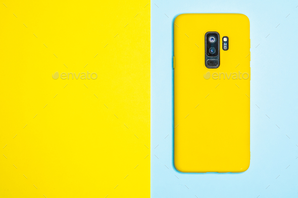 Yellow mobile phone put vertically in the blue and yellow background ...